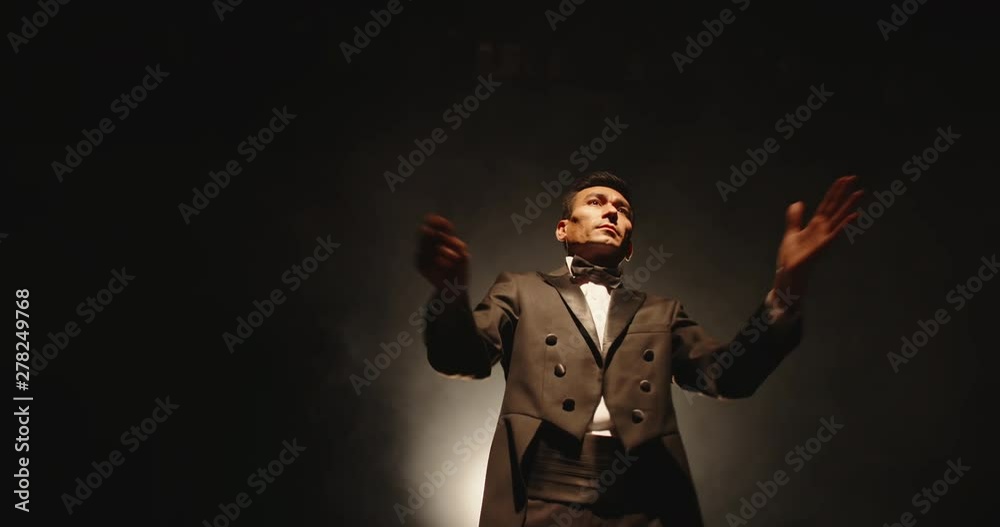 Asian symphony orchestra conductor wearing suit is directing musicians ...