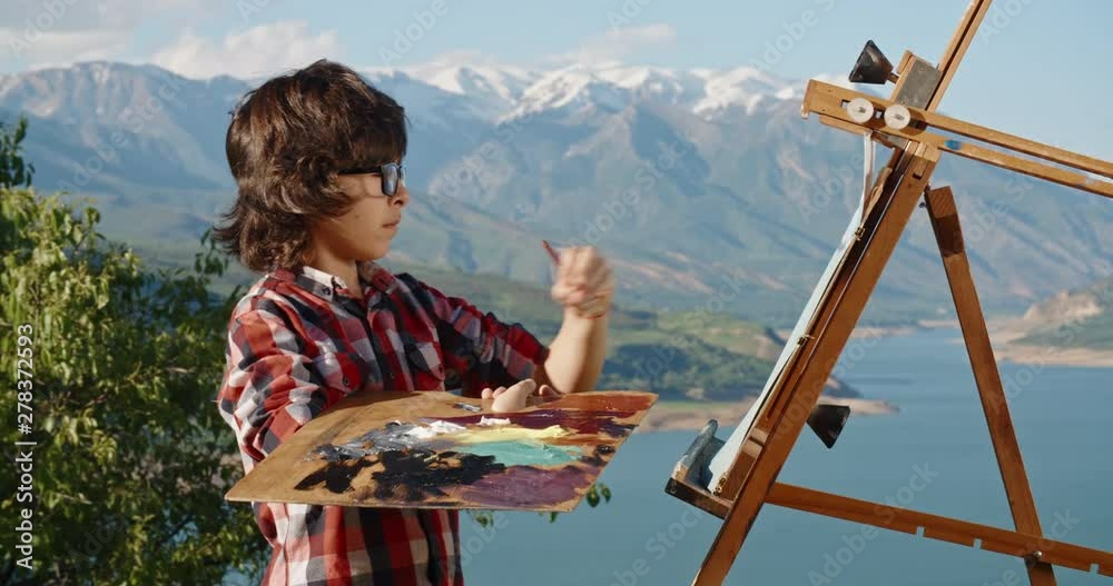 Young kid standing in front of easel, learning how to draw, creating a ...