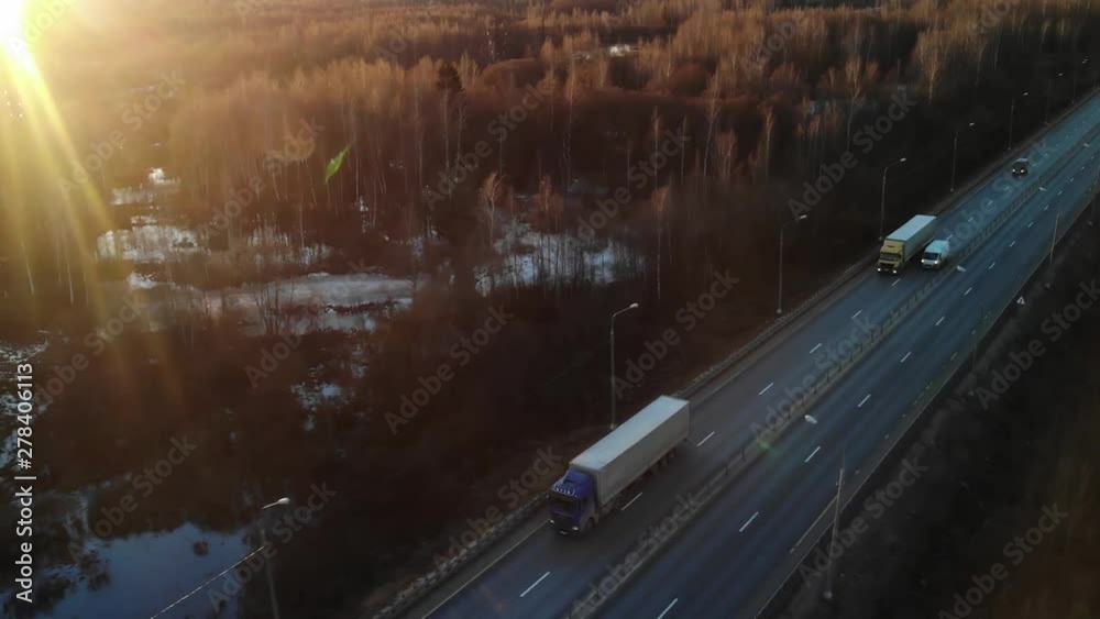 Cars and freight semi trucks loaded with goods driving along an empty ...