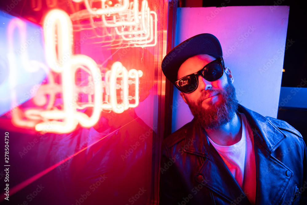 Hipster handsome man on the city streets being illuminated by neon ...