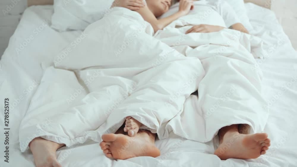 Vidéo Stock couple touching legs, embracing and kissing while lying in ...