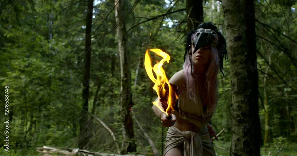 wild female hunter with torch in hand is moving in forest warily in ...