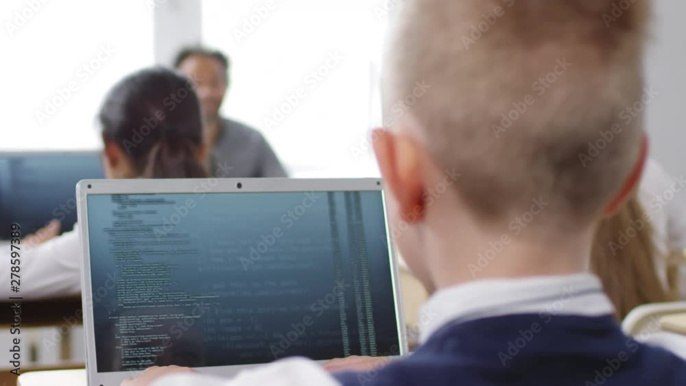 Over-shoulder arc shot of teenage schoolboy in uniform developing ...