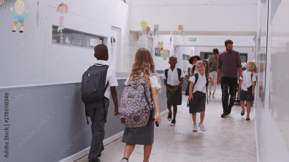 Teacher And Pupils Walking Along Corridor In Busy Elementary School ...