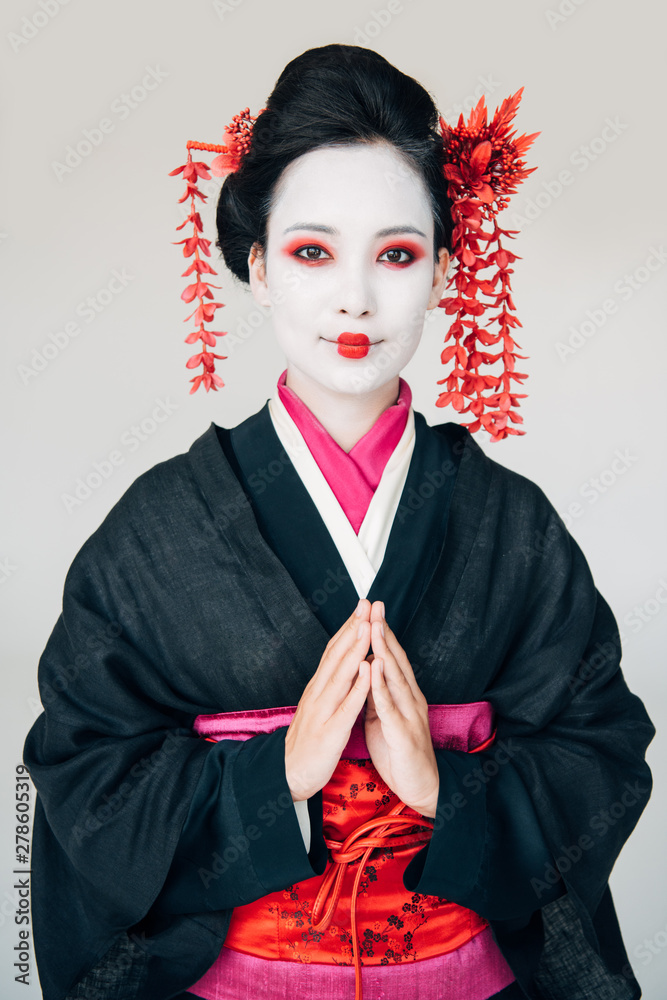 smiling beautiful geisha in black kimono with greeting hands isolated ...