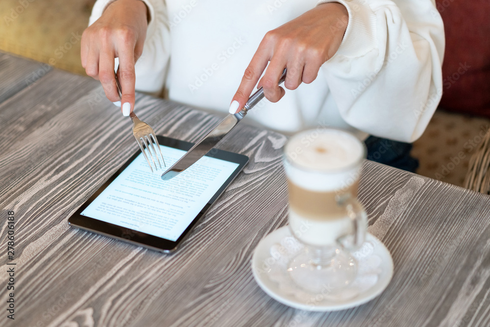 reading an e-book with an appetite. Fork, knife, cafe. concept of ...