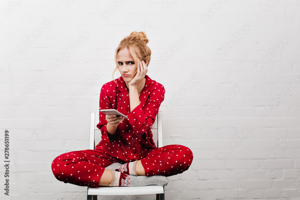 Upset girl in cute socks sitting on chair and waiting for call. Indoor ...