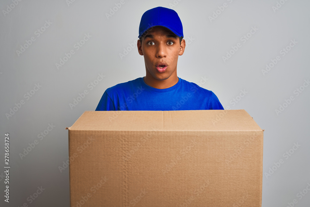 Young handsome arab delivery man holding a box standing over isolated ...