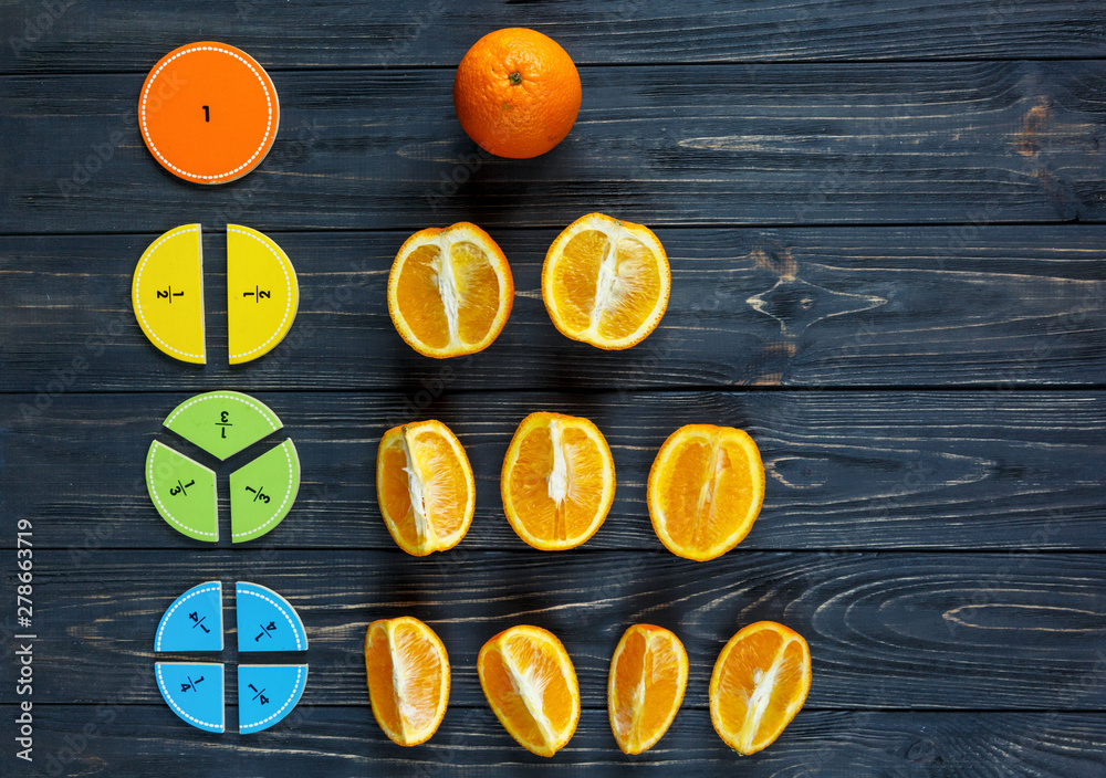 Сolorful math fractions and oranges as a sample on dark wooden ...