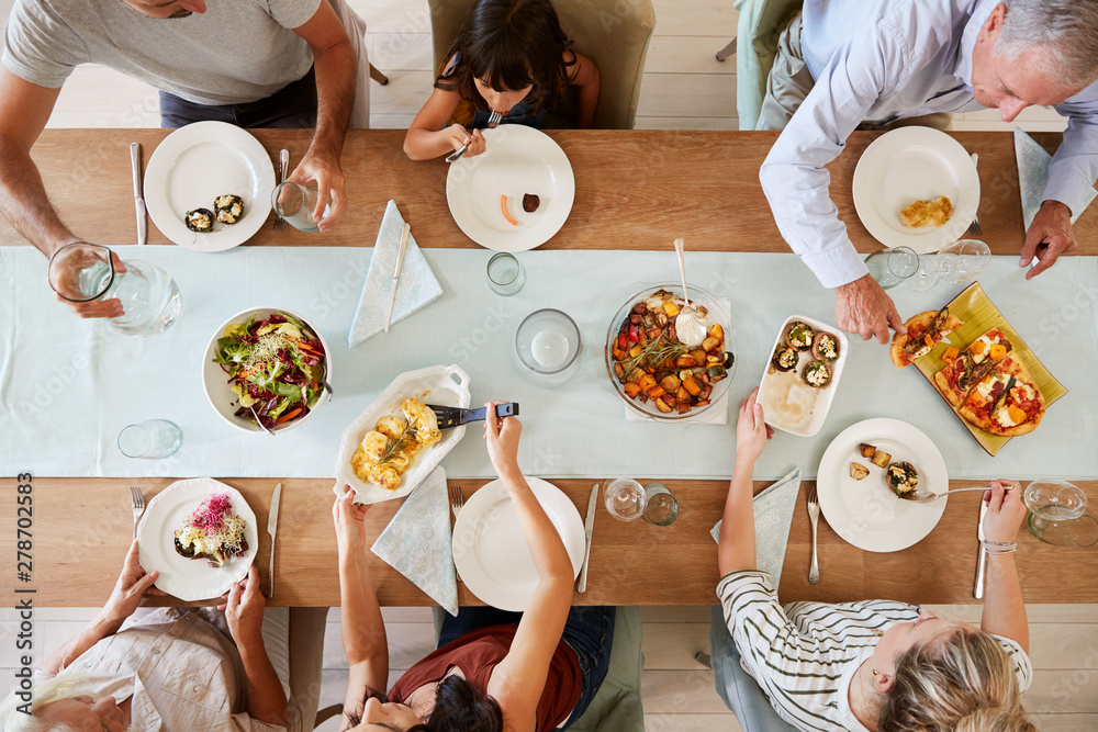 Three generation white family sitting at a dinner table together ...