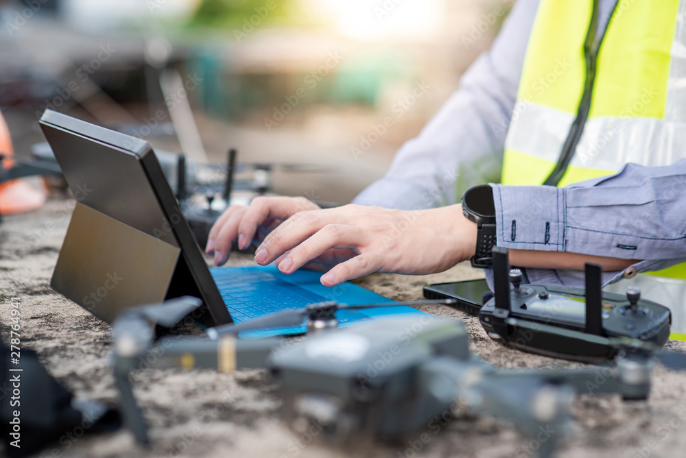 Male worker using drone, remote control and laptop computer at ...