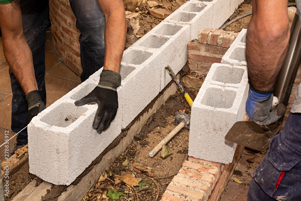 Obreros trabajando en la construcción de un muro con bloques de ...