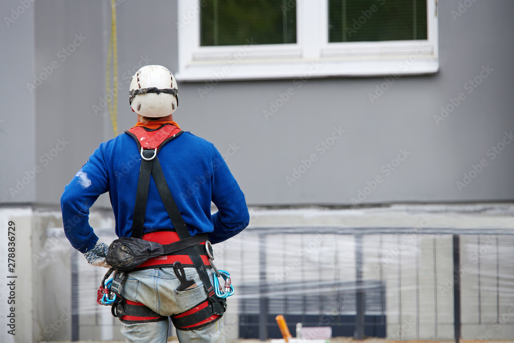 Professional industrial alpinist with rigging equipment, hardhat and ...