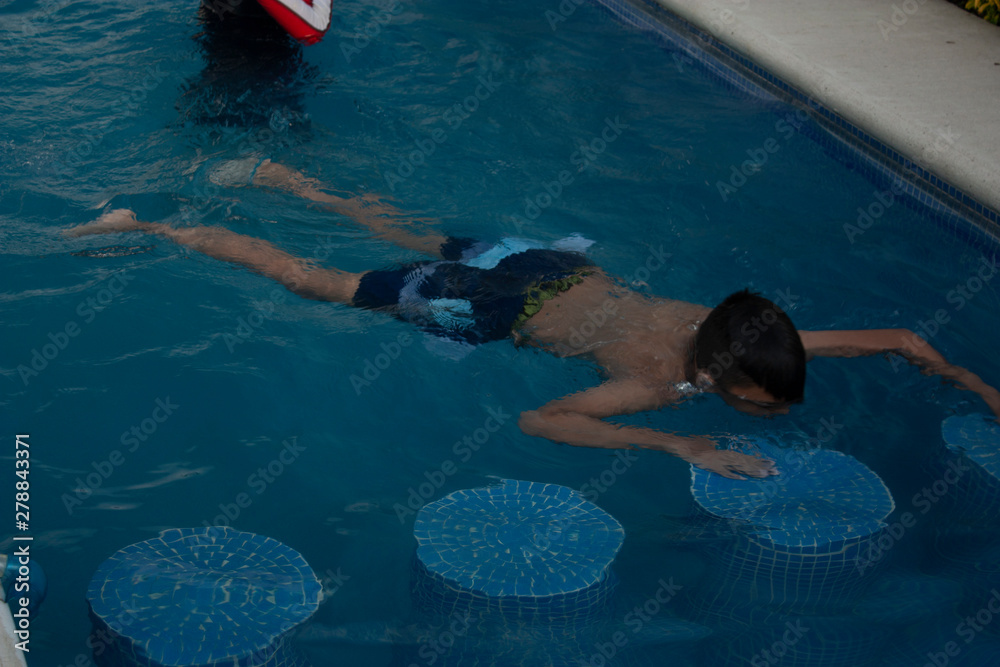 child looking down prone position doing little busts in the water while ...