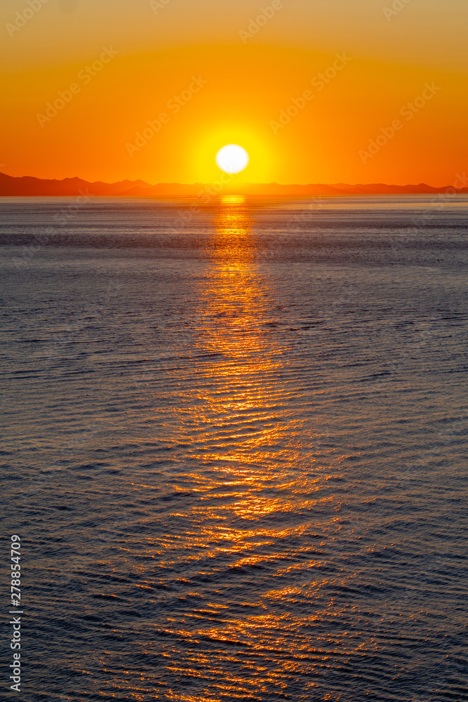 Beautiful golden sunset/sunrise over the sea behind mountains in ...