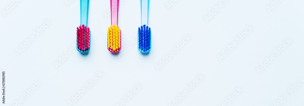 Colorful tooth brushes with bright color bristles on a light pastel ...