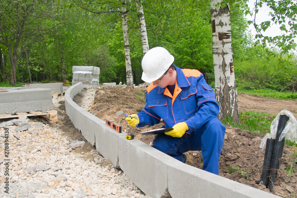 the builder, in a white helmet, blue uniform and yellow gloves, checks ...