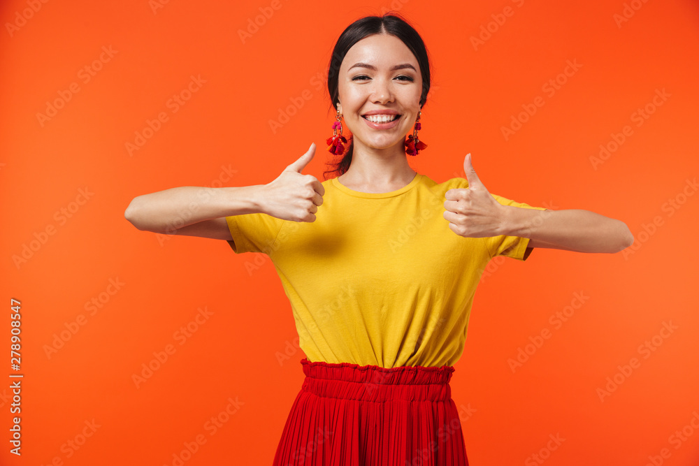 Excited happy young woman posing isolated over orange wall background ...