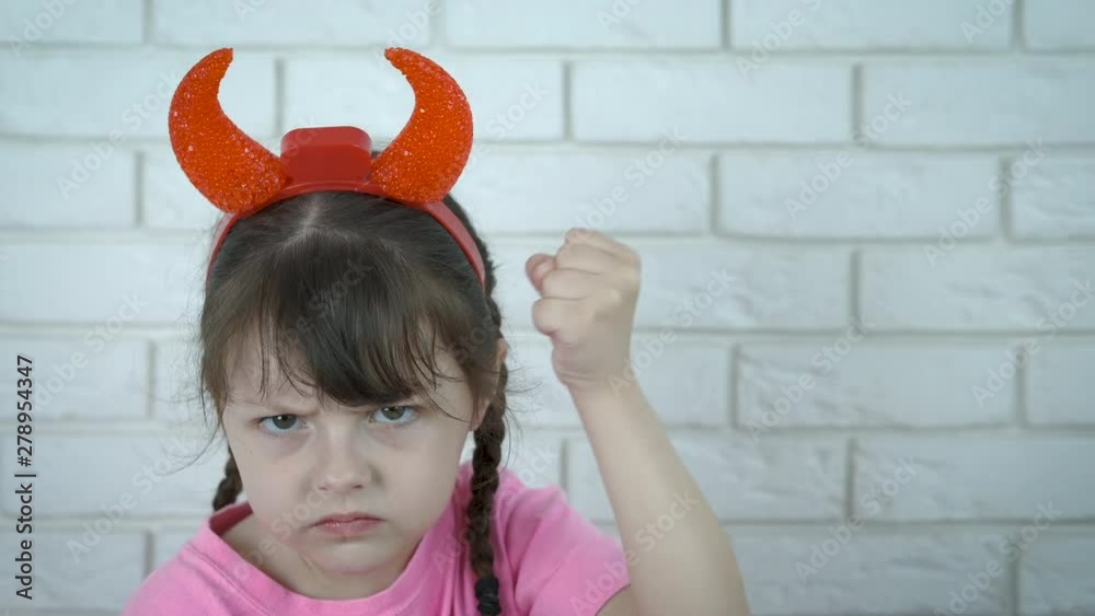 A child with demon horns. Angry little girl in devil horns. Evil child ...