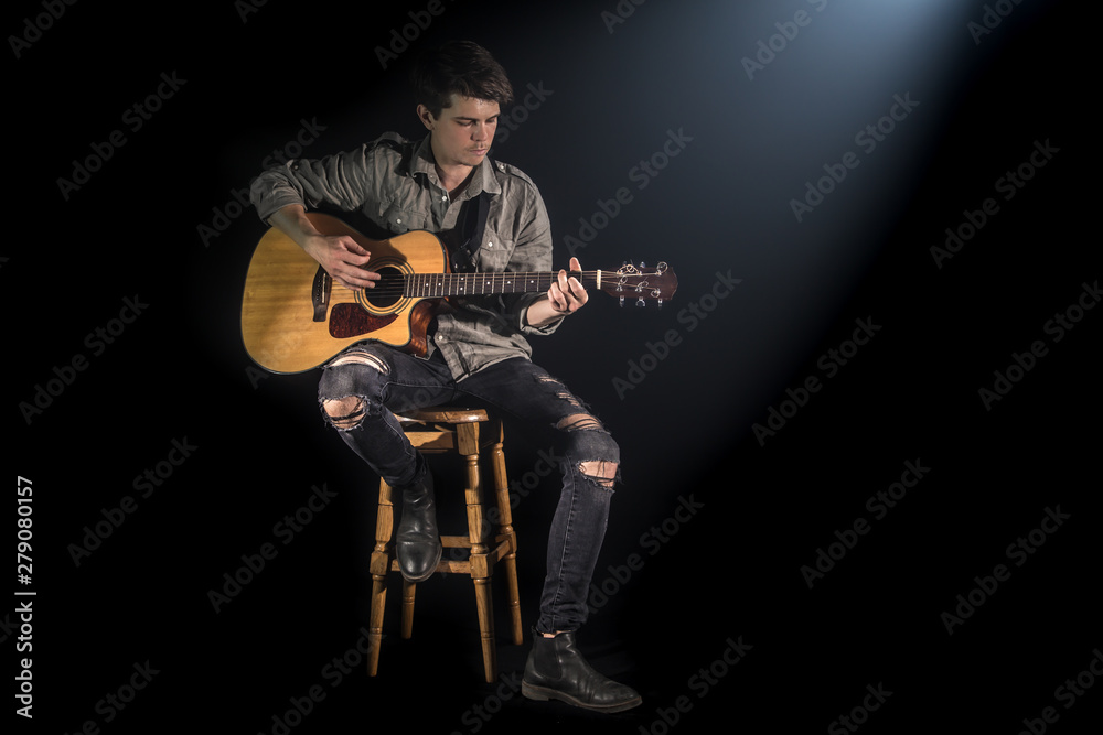 musician playing acoustic guitar, sitting on high chair, black ...