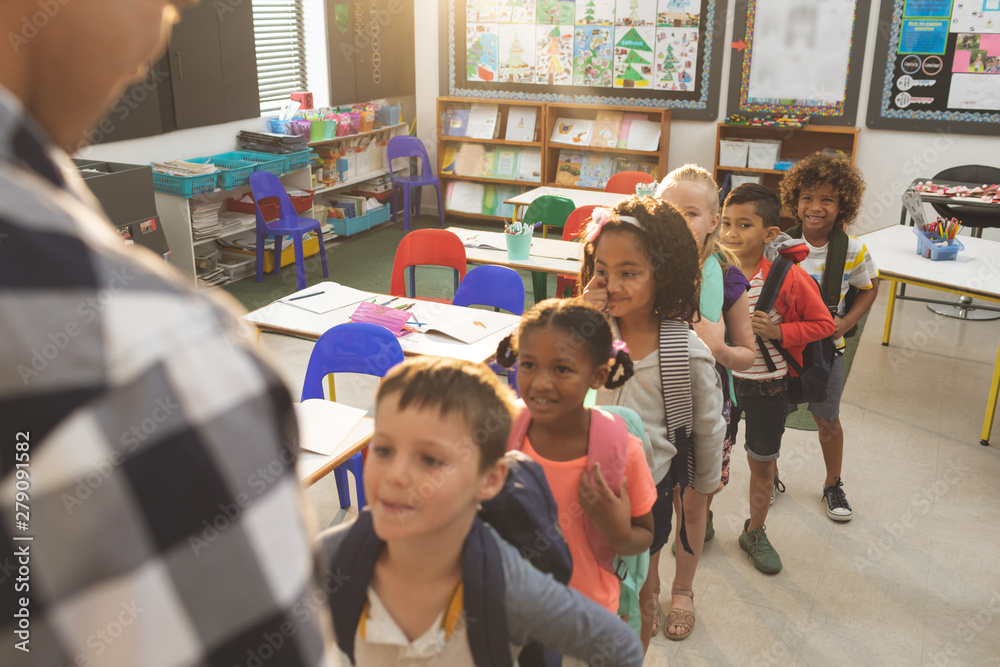Foto de School kids standing and forming a queue in classroom at school ...