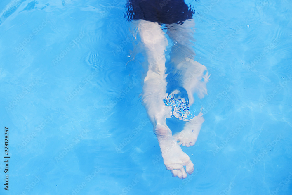 boy swims in the pool. boy learning to swim. feet in the pool close ...