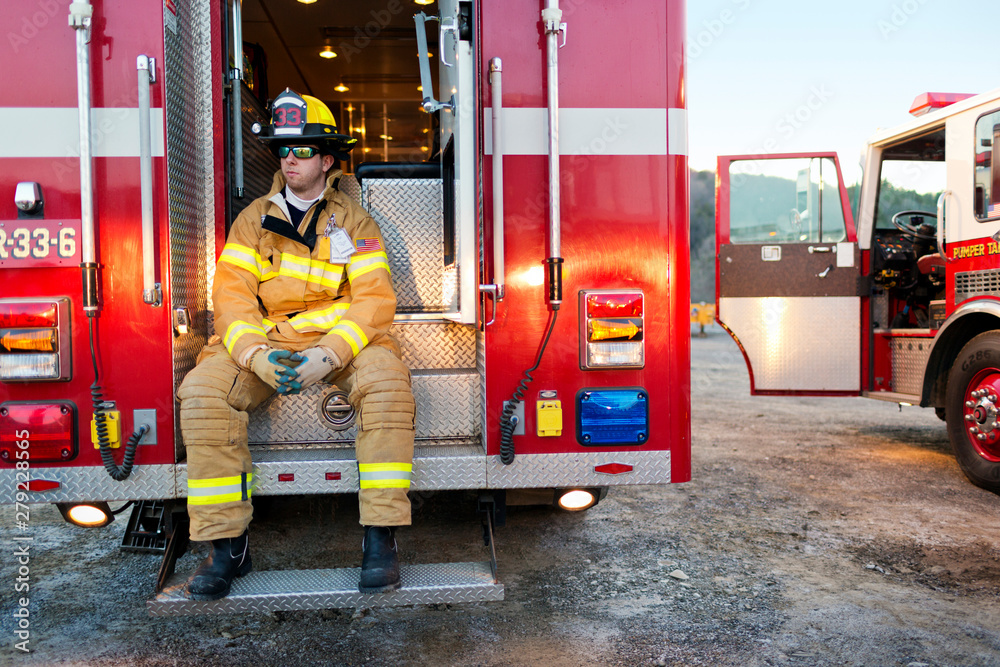 Firefighter sitting on back of fire engine Stock Photo | Adobe Stock