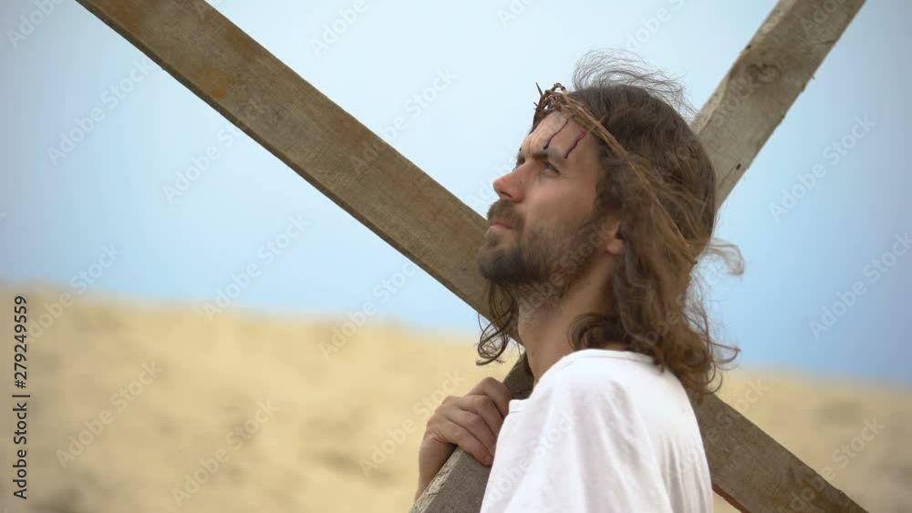 Jesus Christ with crown of thorns carrying cross, praying to God for ...