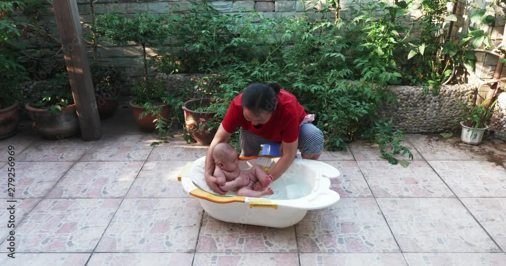 Senior Chinese grandmother putting her newborn granddaughter into the ...