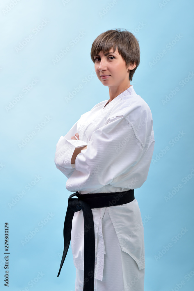 Young karate woman in a white kimono with black belt demonstrates ...