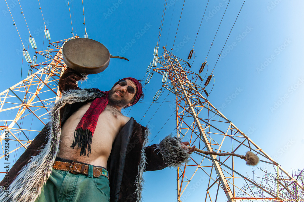 Sacred man beneath electricity towers. A young Caucasian shaman is ...