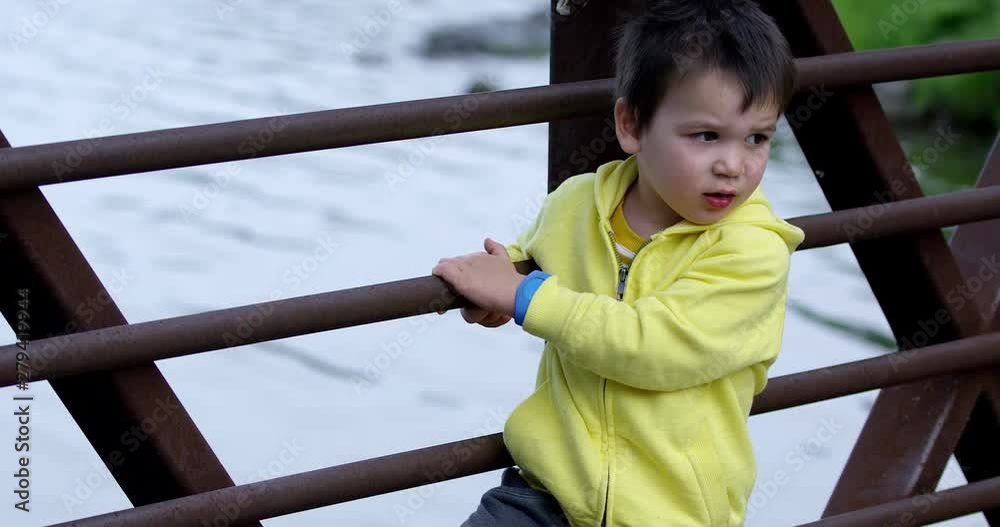Toddler boy in an upset mood turns to face camera with not impressed ...