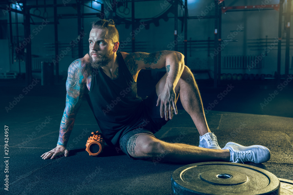 Young healthy man athlete doing exercise with the roller in the gym ...