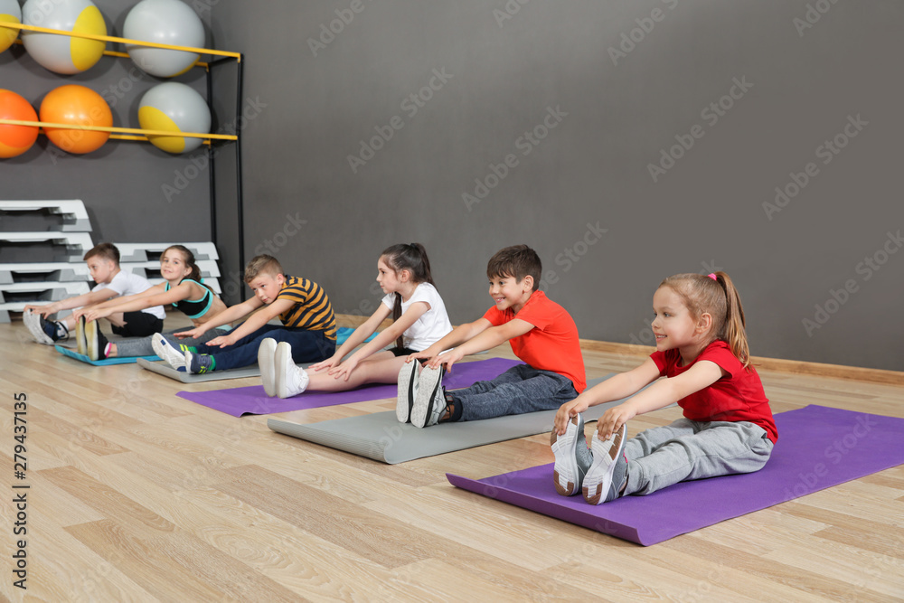 Cute little children sitting on floor and doing physical exercise in ...