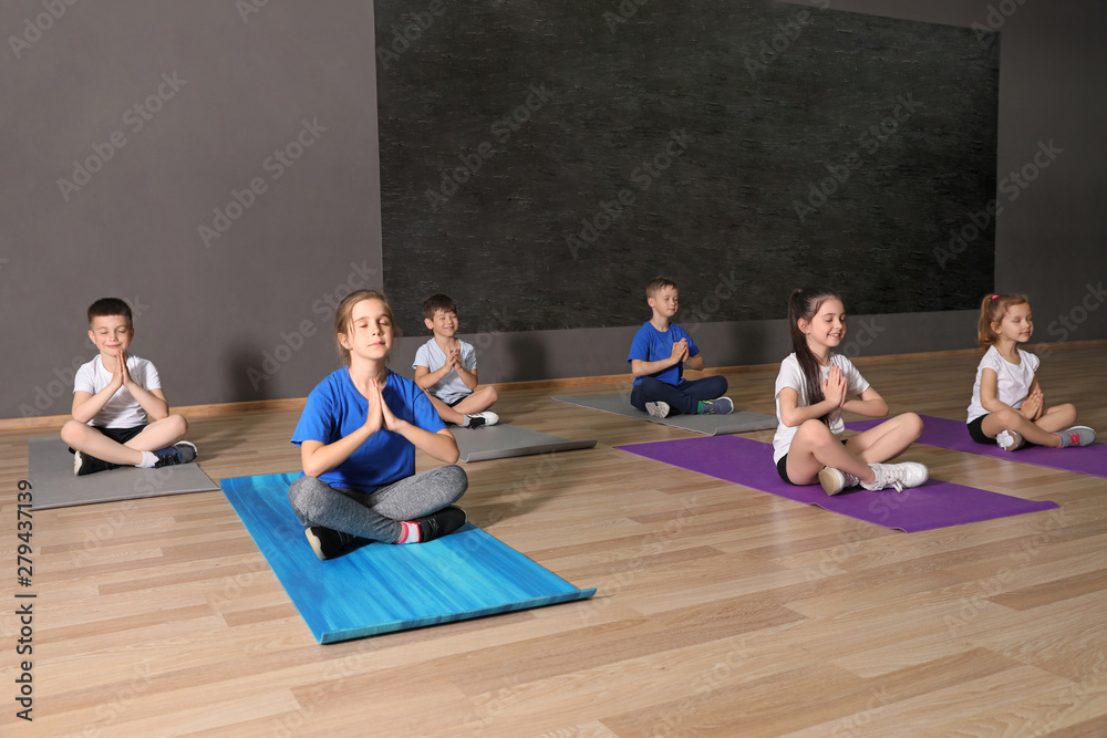 Cute little children sitting on floor and doing physical exercise in ...