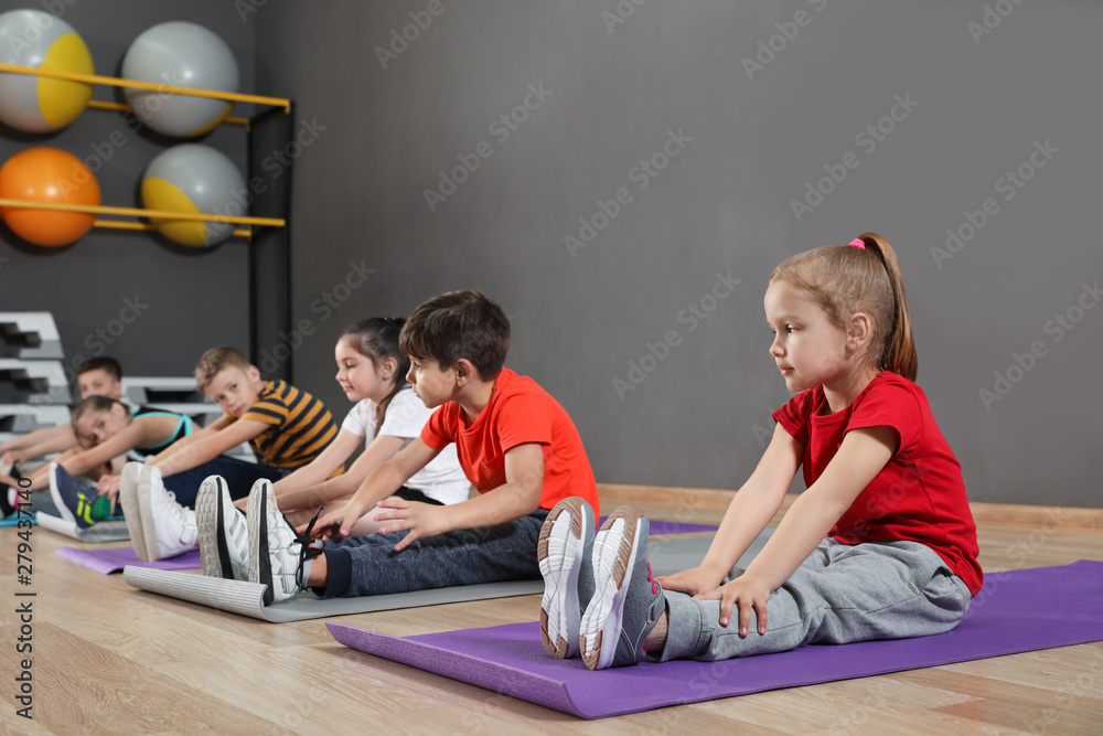 Cute little children sitting on floor and doing physical exercise in ...