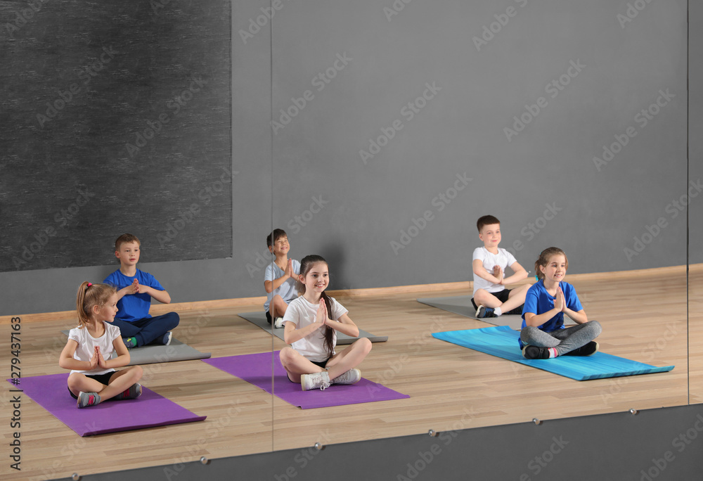 Cute little children sitting on floor and doing physical exercise in ...