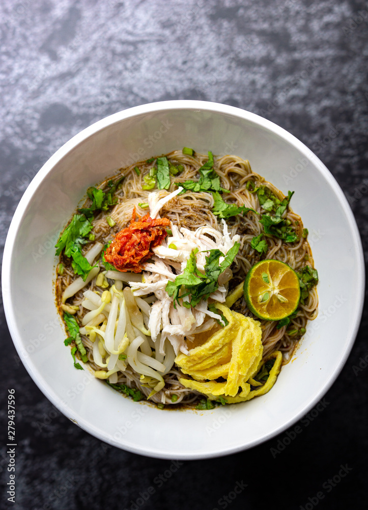 A traditional Sarawak Laksa in white bowl on dark background.It's a ...