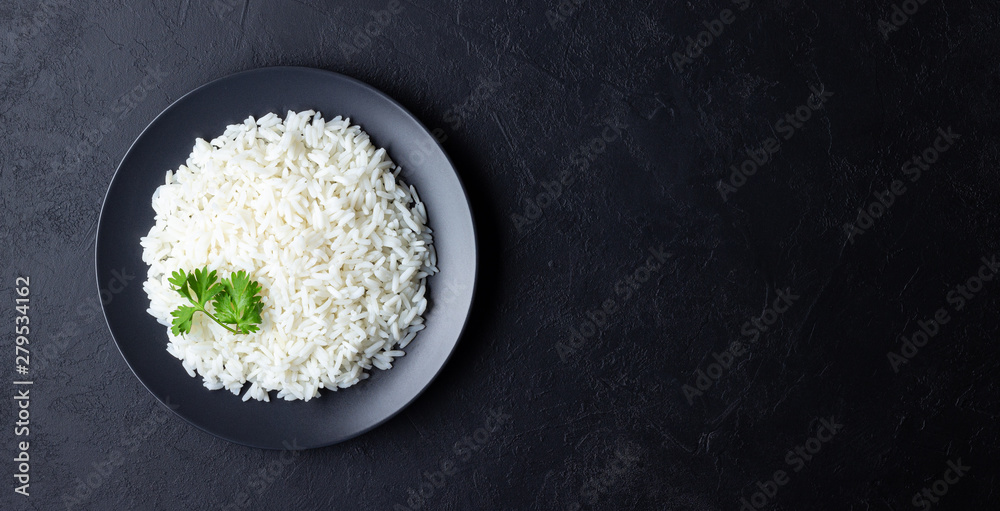 Steamed rice on black plate. Black stone background. Top view with copy ...