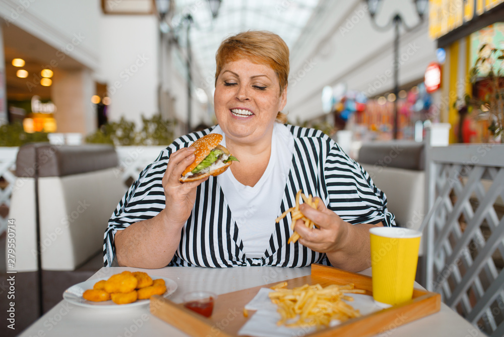 Fat woman eating high calorie food in restaurant Stock Photo | Adobe Stock