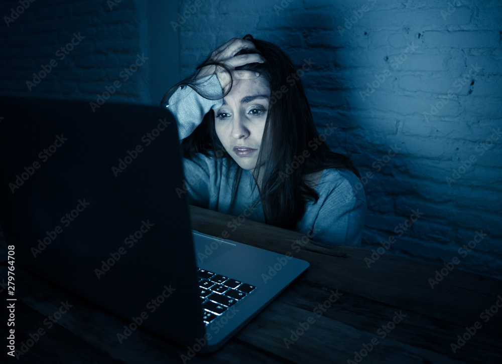 Scared woman on laptop in the dark feeling fear suffering online ...