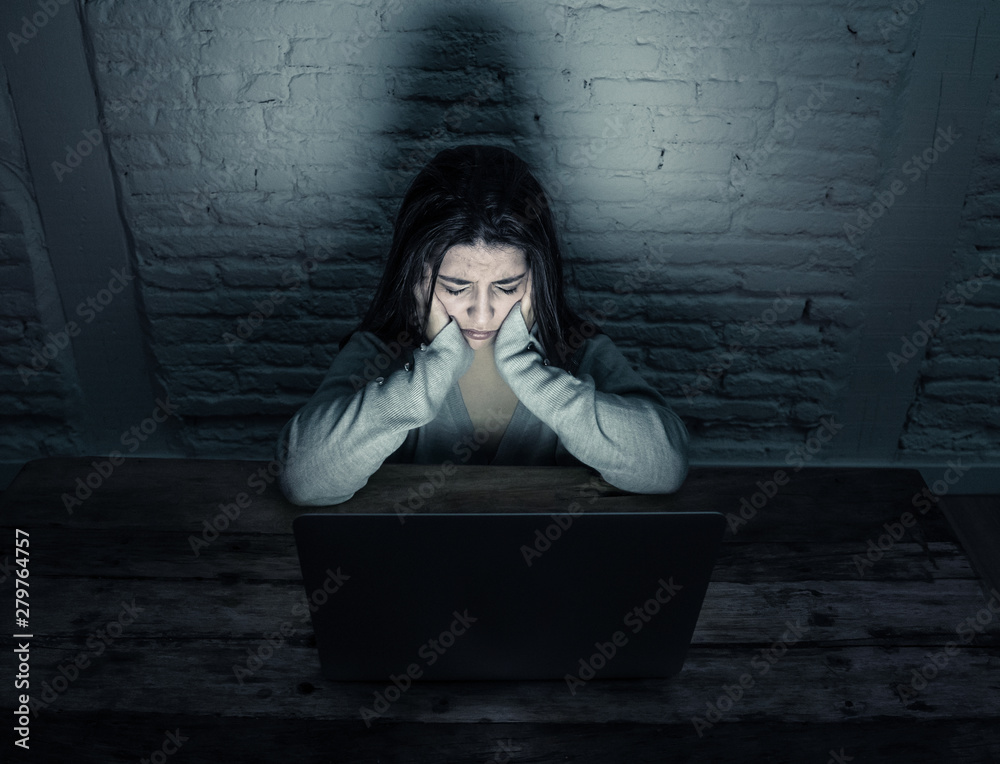 Scared woman on laptop in the dark feeling fear suffering online ...