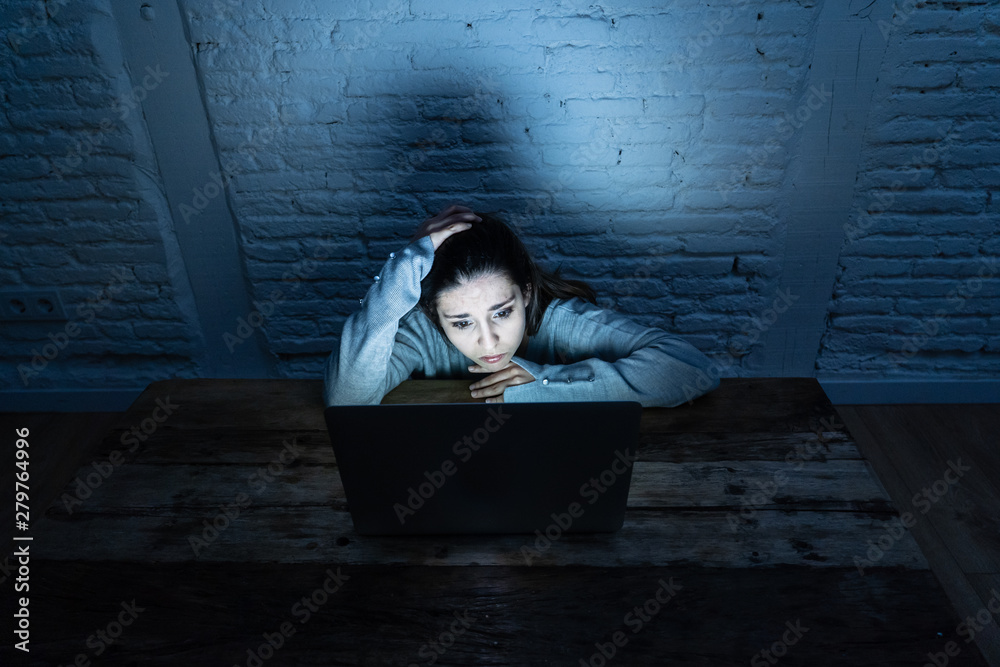 Scared woman on laptop in the dark feeling fear suffering online ...