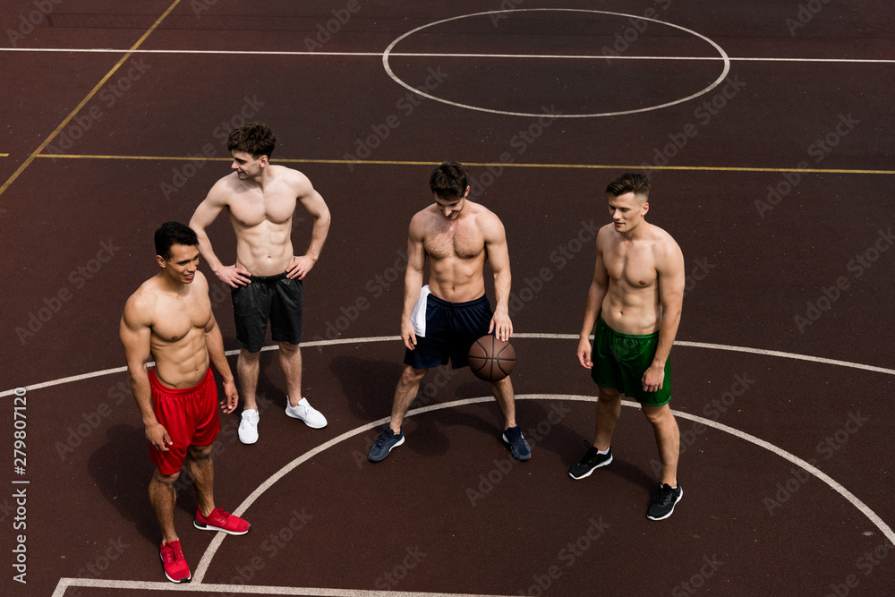 overhead view of four shirtless basketball players with ball at ...