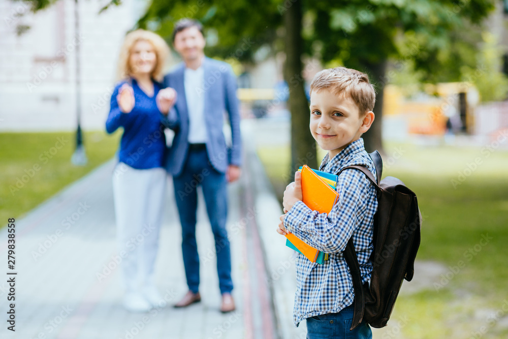 Two mature parents seeing their little child off to school. Pupil with ...