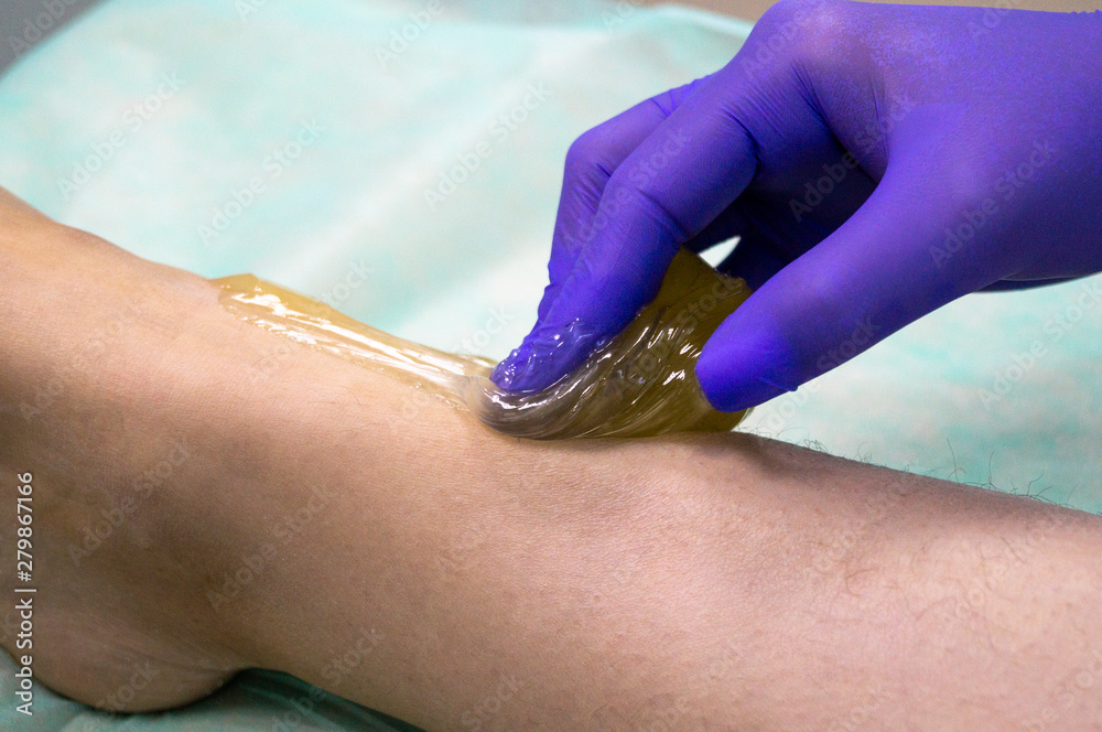 The master in the salon makes the girl sugaring her legs. Natural ...