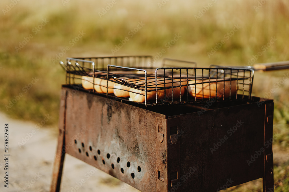 Delicious grilled sausages resting on the iron grid of a portable ...