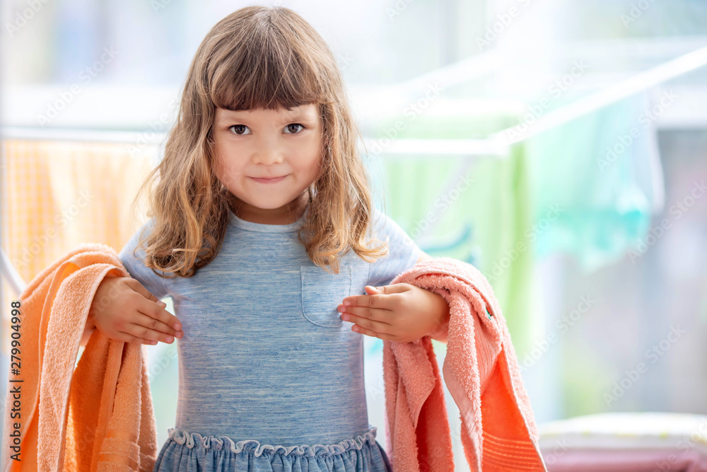 Child in laundry room. Clean washed clothes on drying rack. Mother's ...