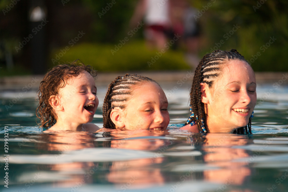 Three children playing piggyback while swimming in a pool in Cruz Bay ...