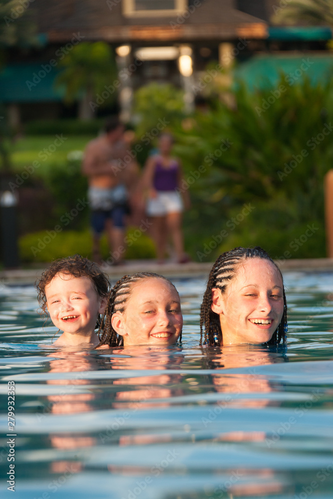 Three children playing piggyback while swimming in a pool in Cruz Bay ...